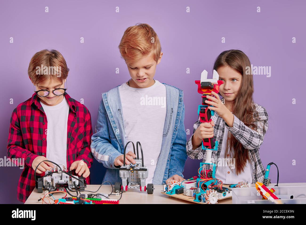 portrait of clever children assembling robots on table, teamwork ...