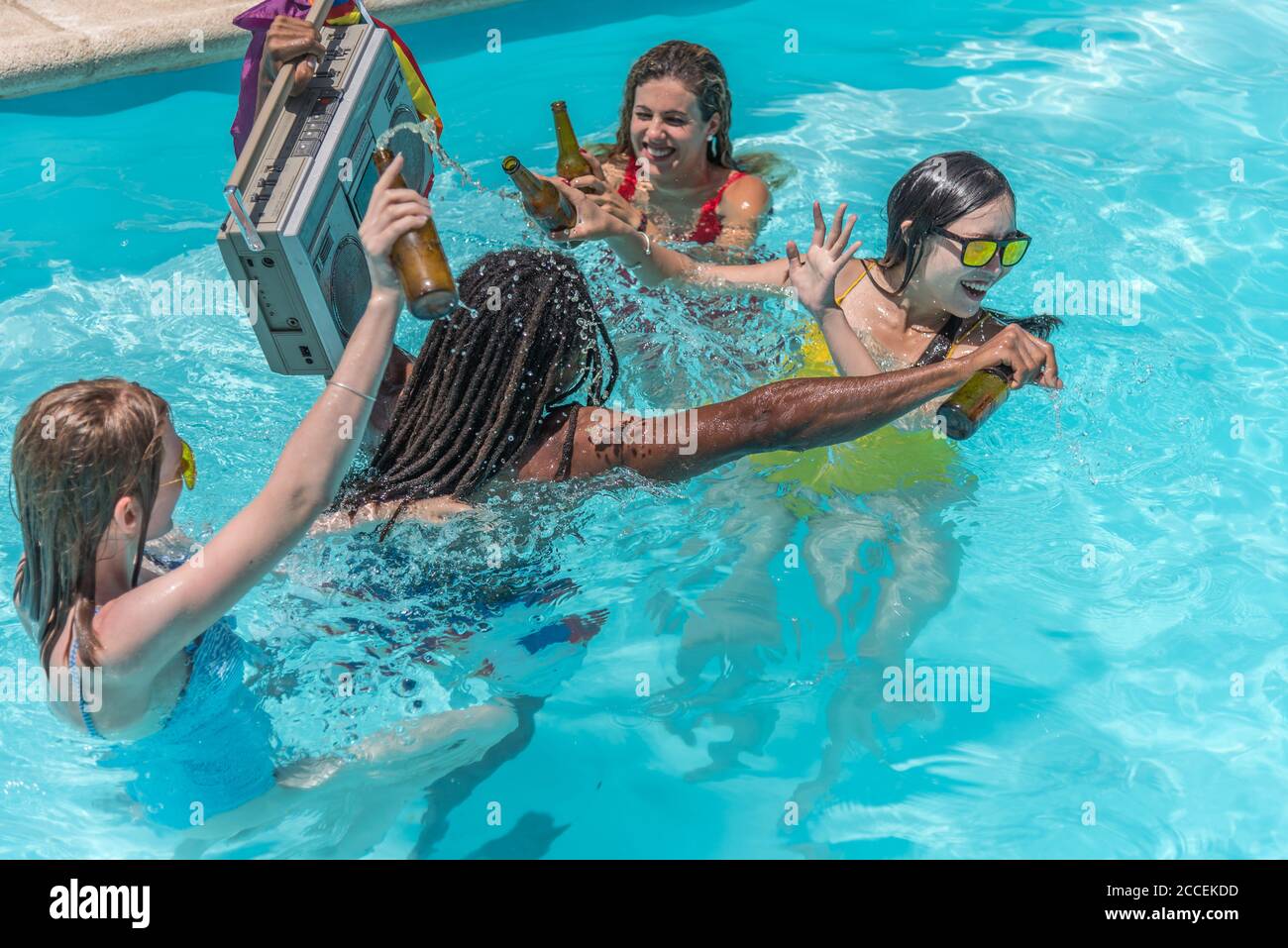 People playing splash around inside a pool with beers while a man ...