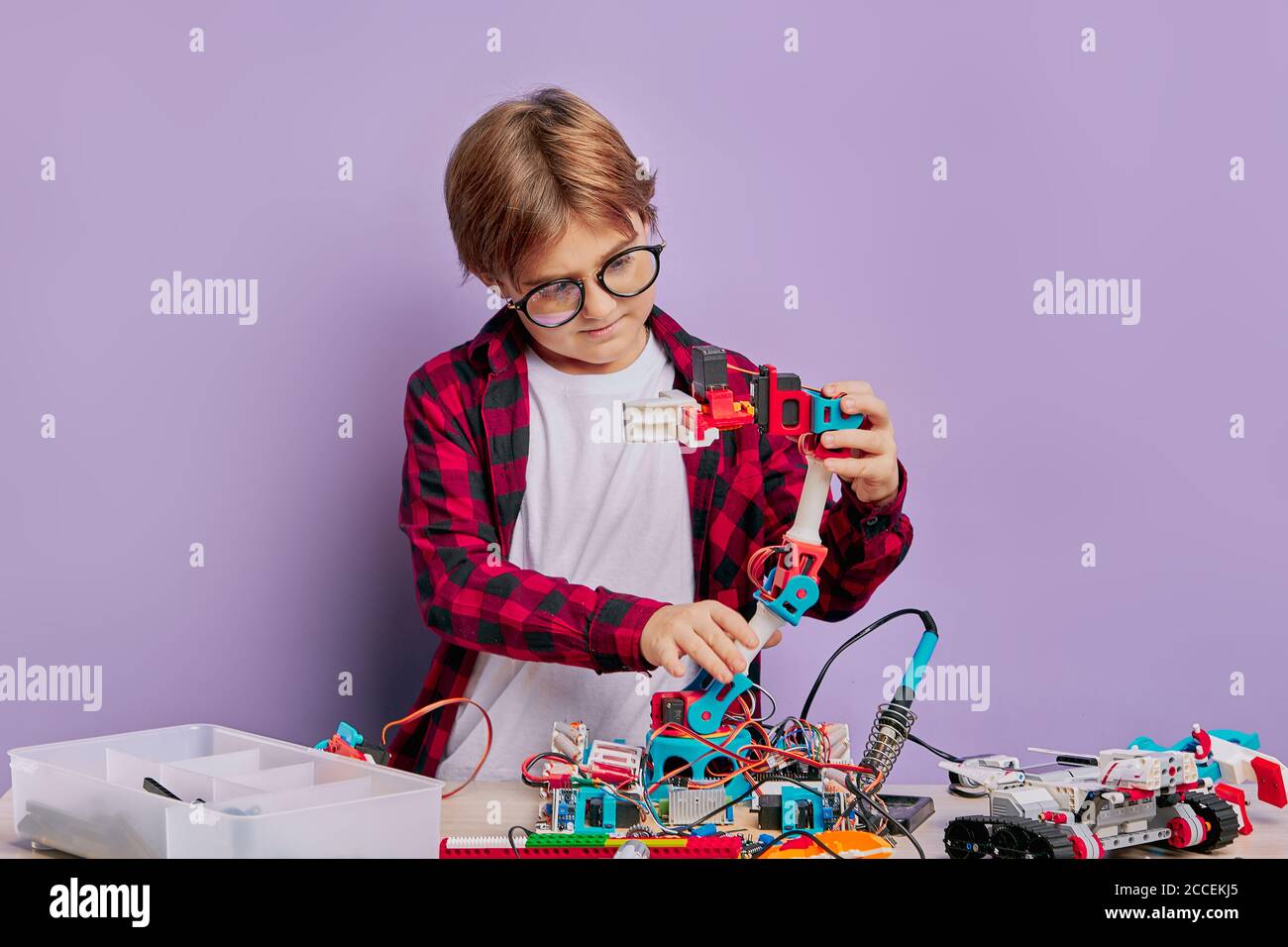 portrait of smart kid boy interestedly studying robots, assembling ...