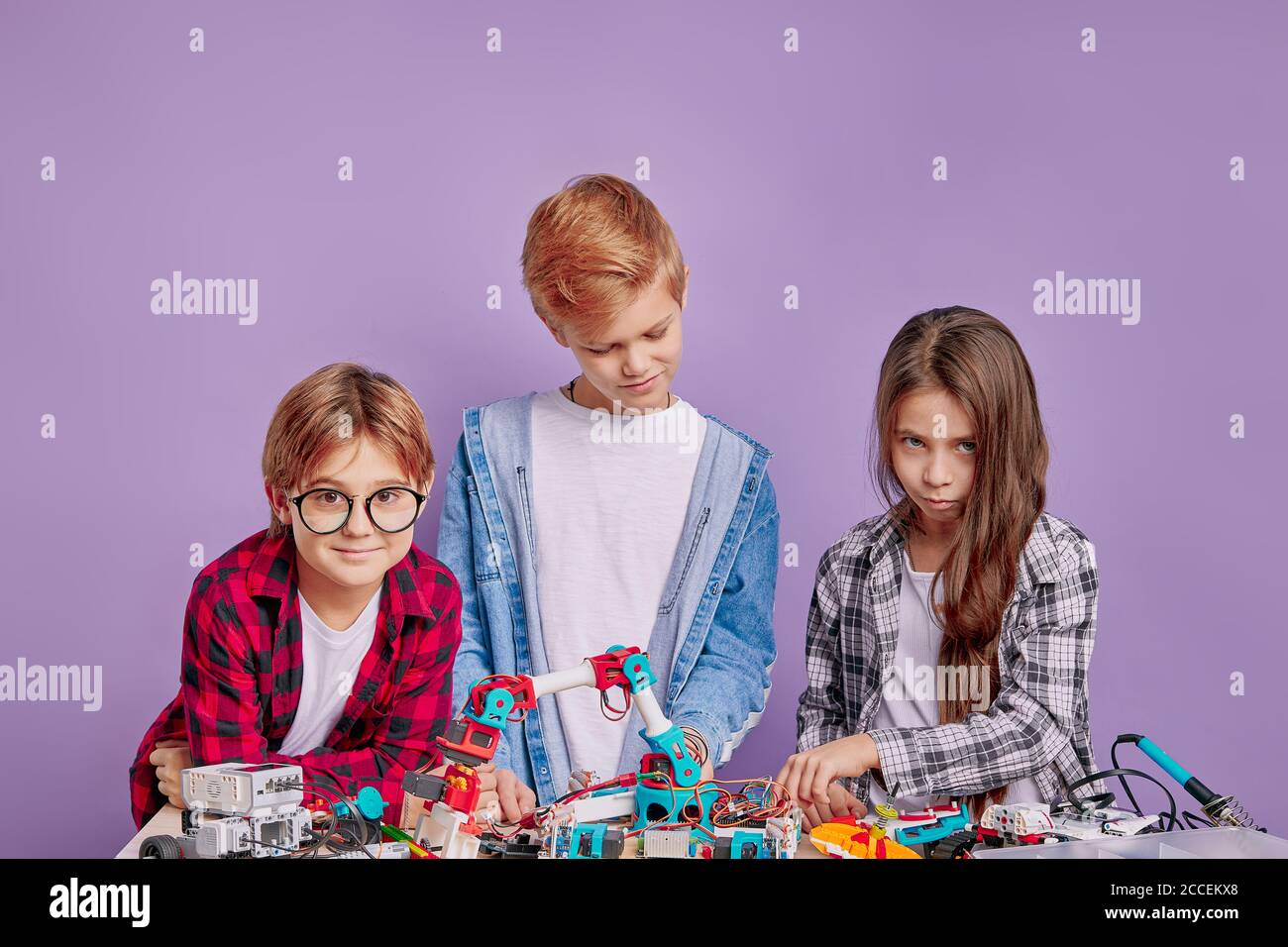 portrait of clever children assembling robots on table, teamwork ...