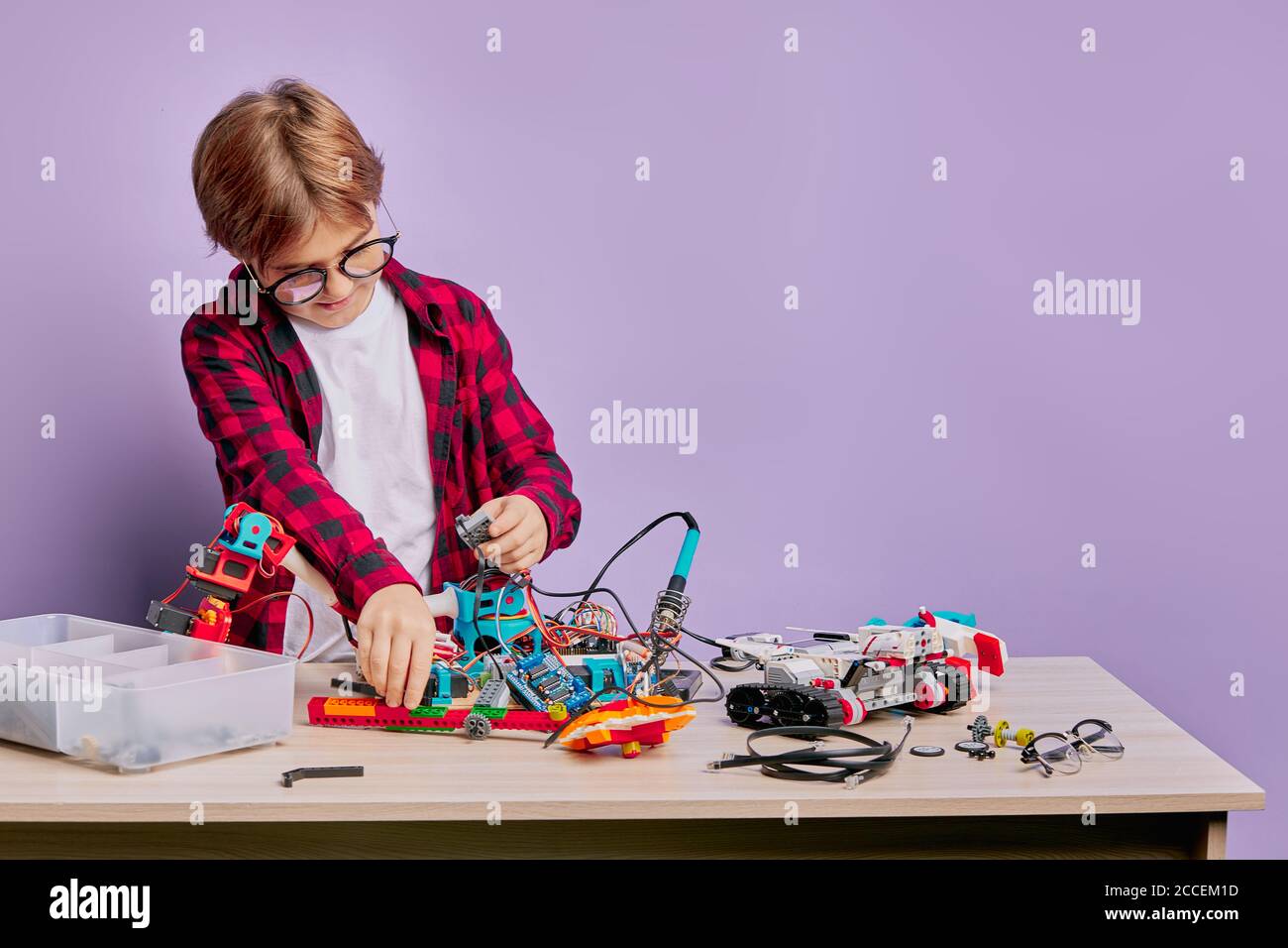 little caucasian kid boy interested in assembling different robots in ...