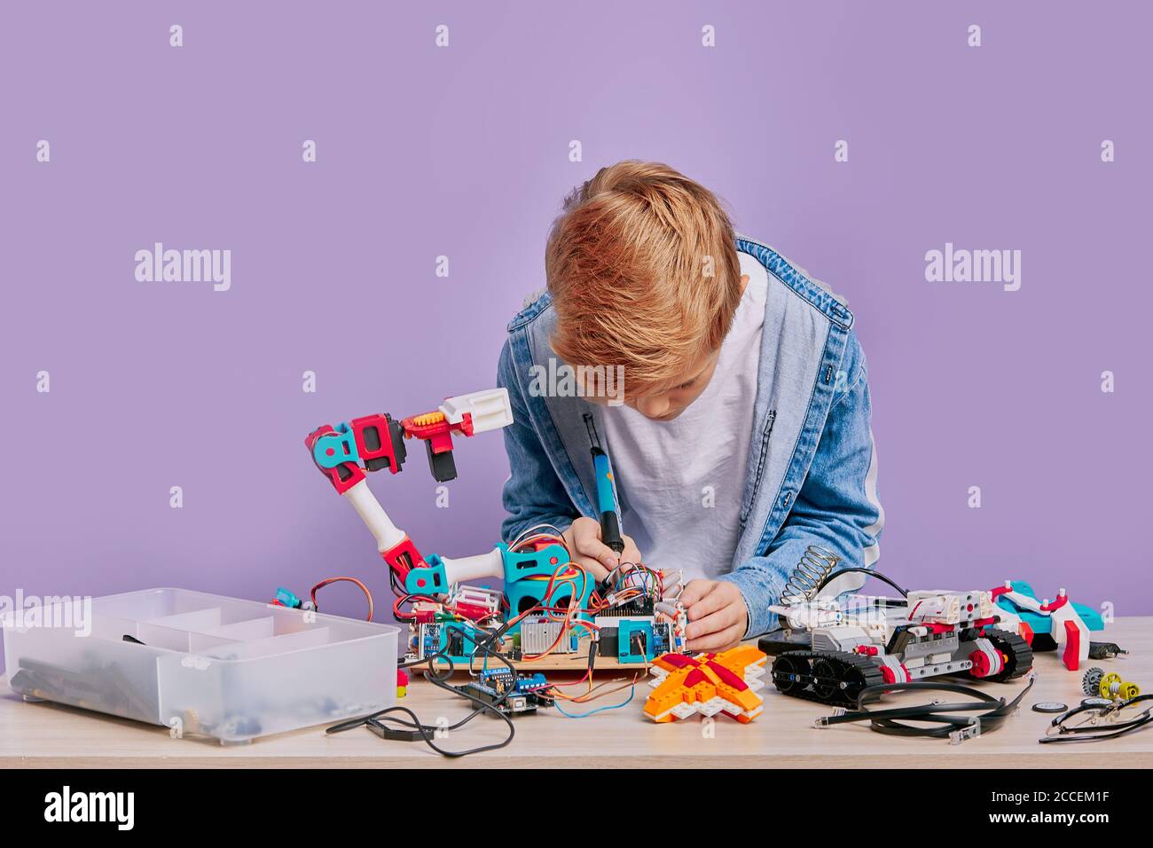 portrait of blond boy concerned with assembling robotics child boy ...