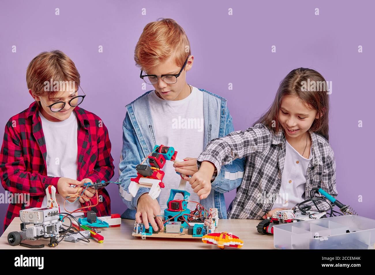 portrait of clever children assembling robots on table, teamwork ...