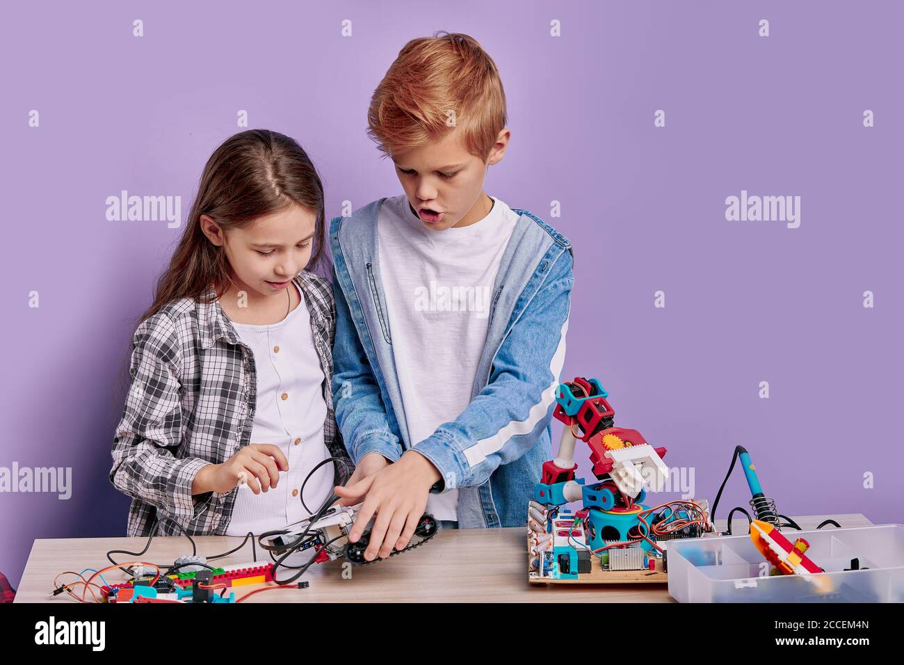 portrait of clever children assembling robots on table, teamwork ...