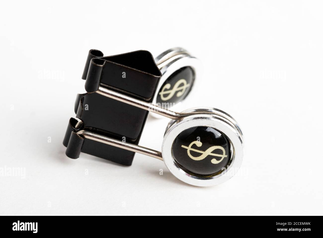 A close-up of a black document clip with a circular press handle ...