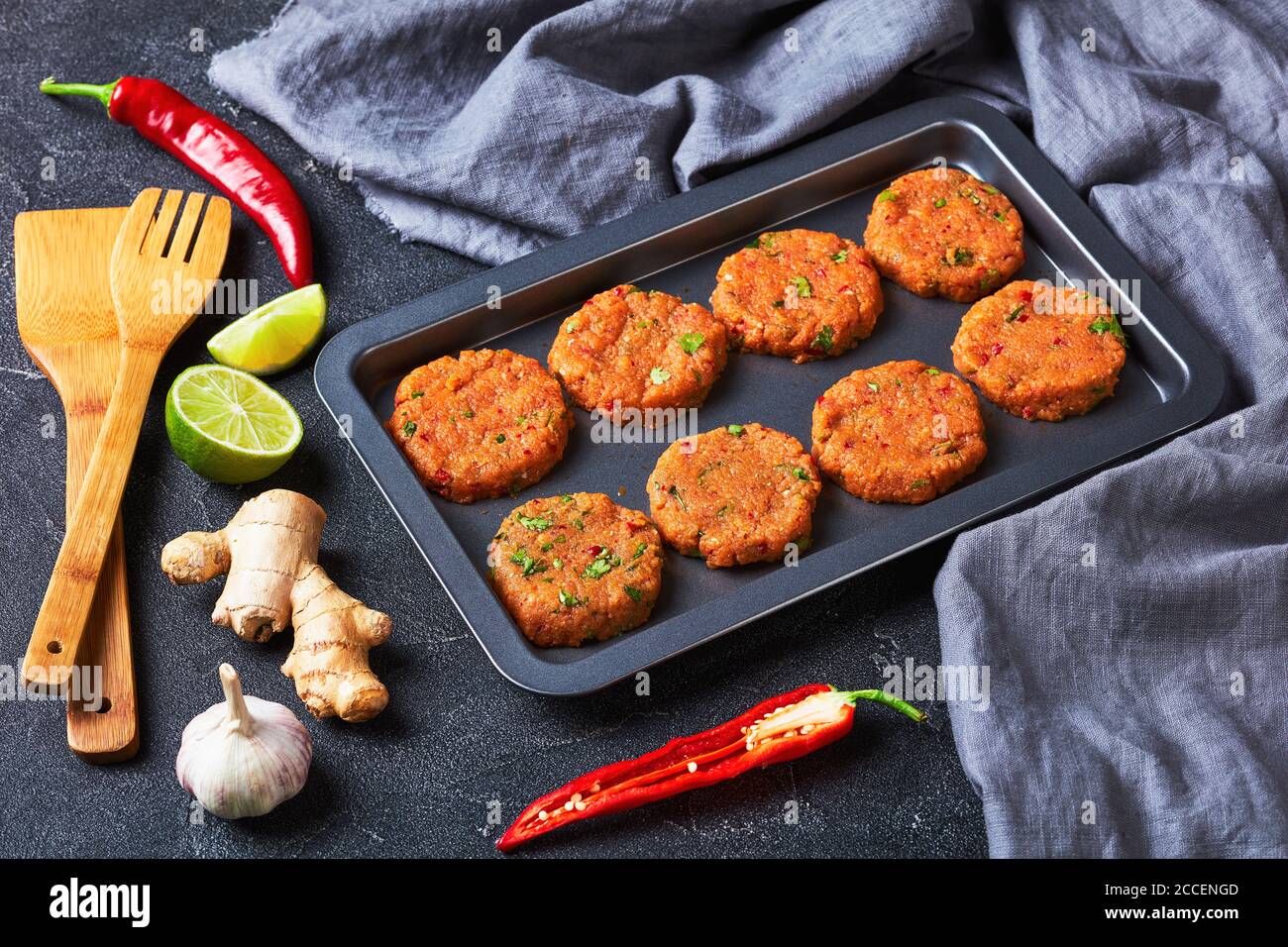raw thai fish cakes prepared on a baking sheet on a concrete table ...