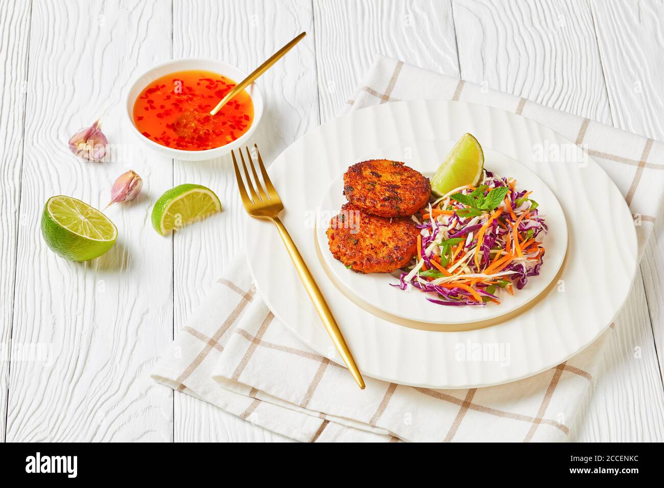 fried thai fish cakes served with coleslaw salad on a plate on a wooden ...