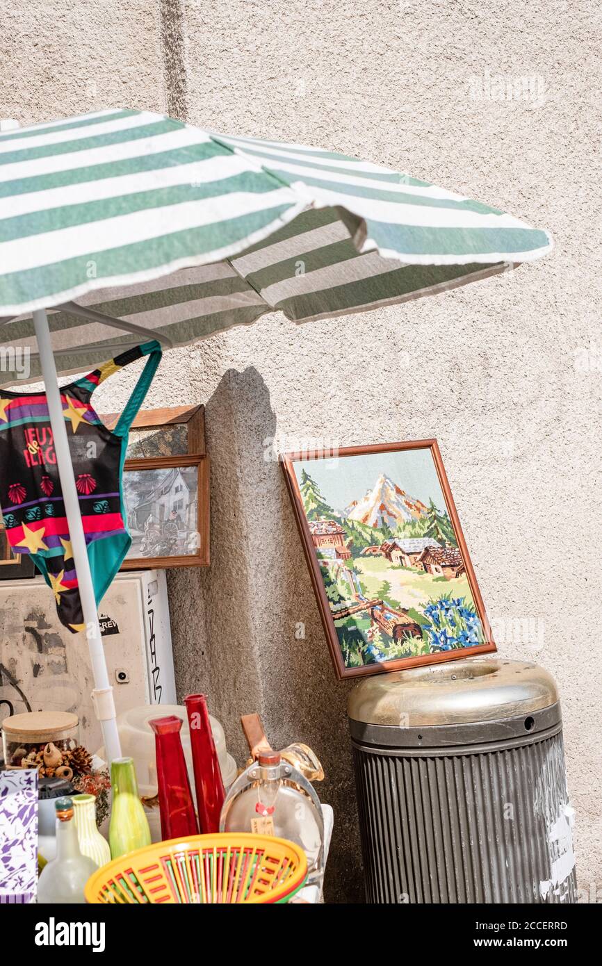 Flea market stall with vases, pictures, swimsuit and parasol in front ...