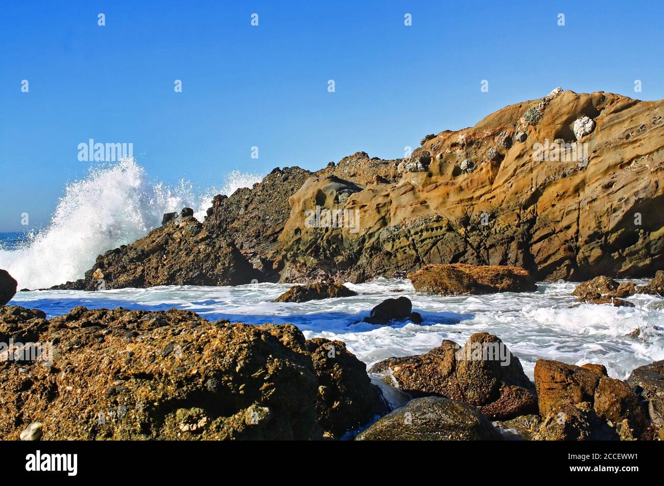 Ocean waves break and splash over sea rocks in a beach cove Stock Photo ...