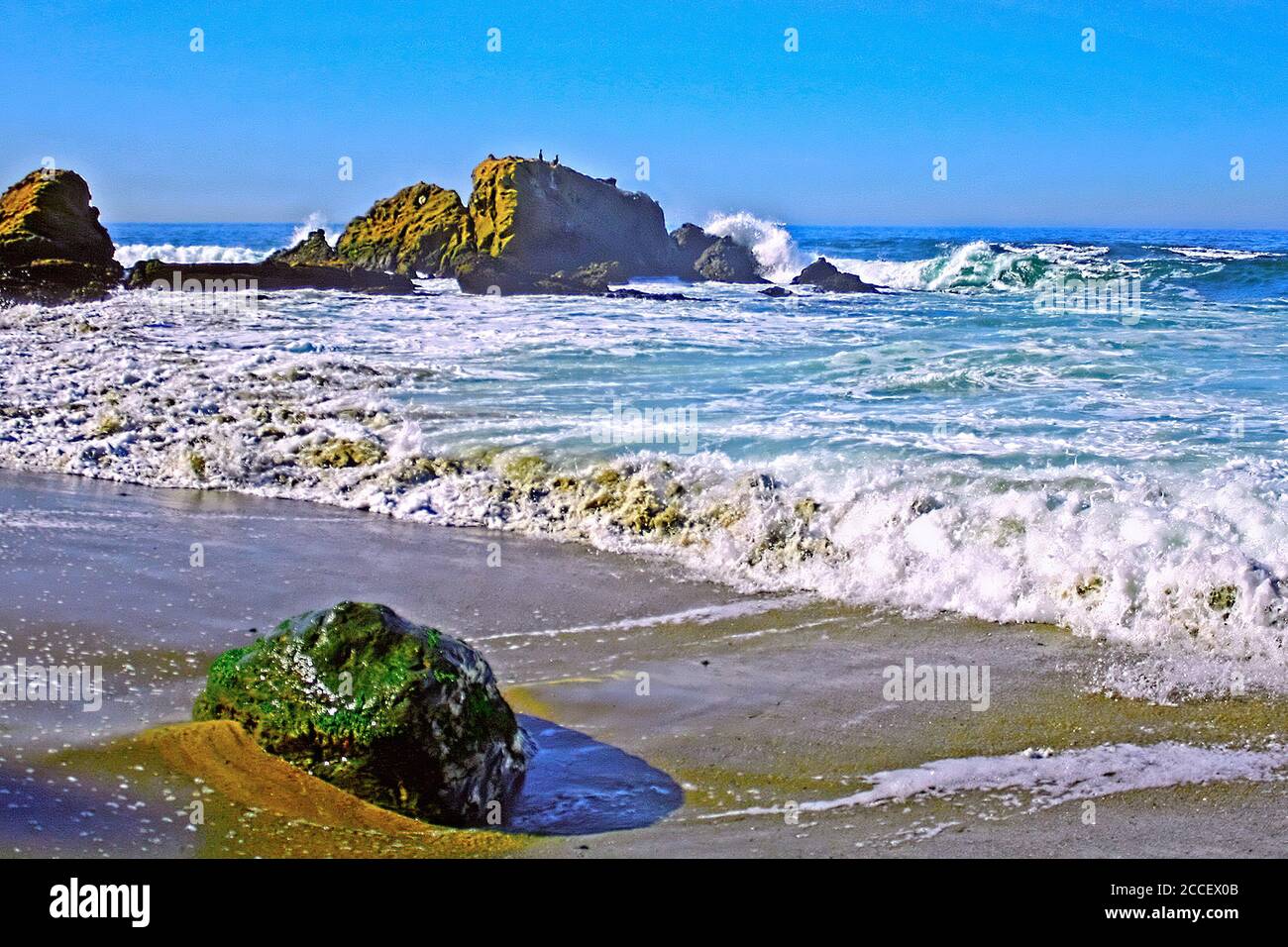 Foamy ocean waved break over rocks near the shore Stock Photo - Alamy