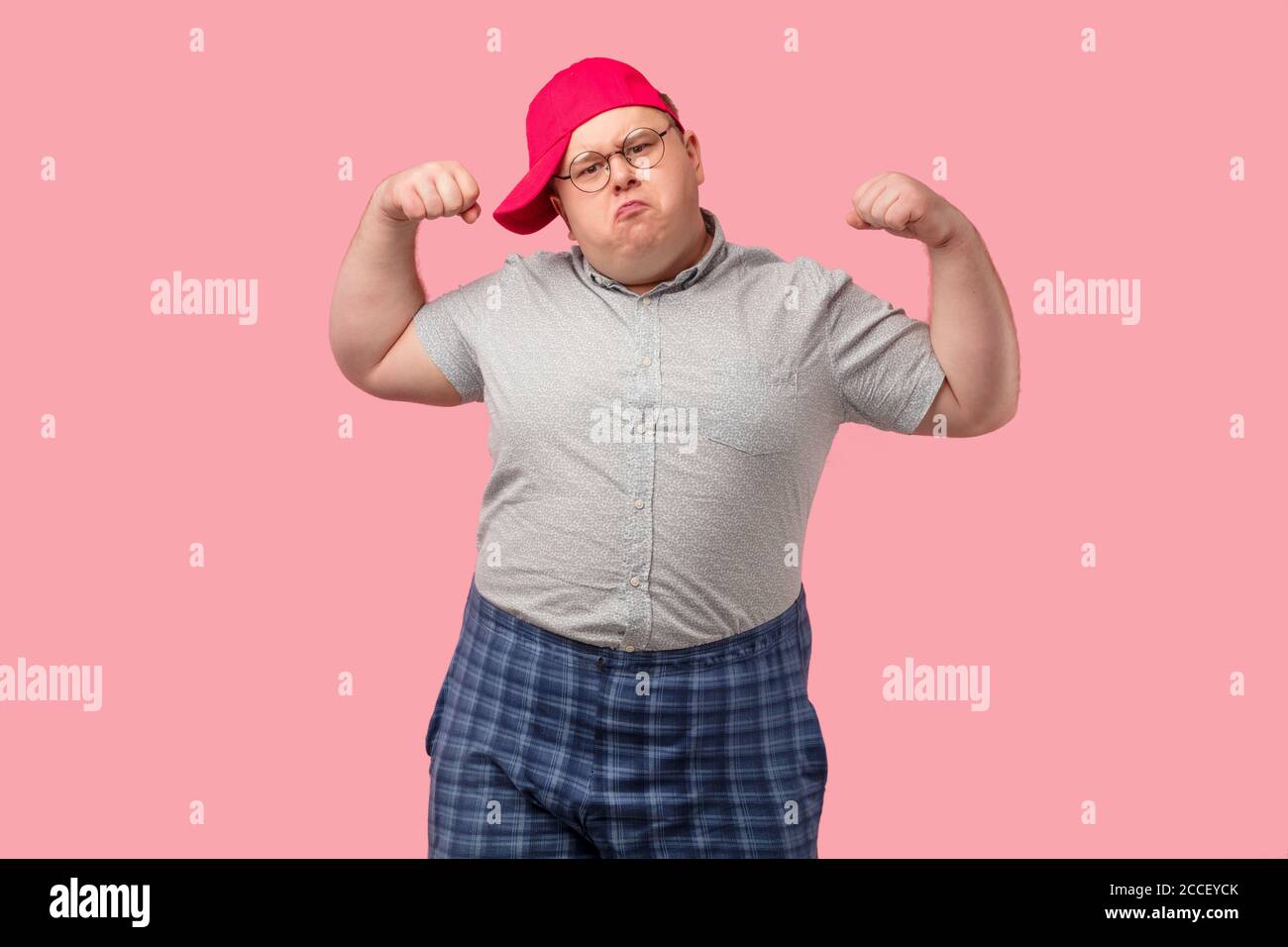 Funny comic overweight man dressed in casual wear shows his muscles ...