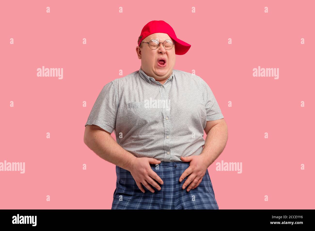 Positive and joyful fat man bursts into laughing, holding his hands on ...