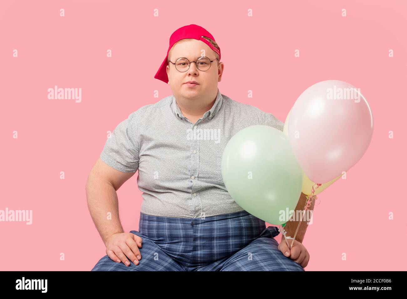 Confident grown up tubby man in red baseball cap and checkered pants ...