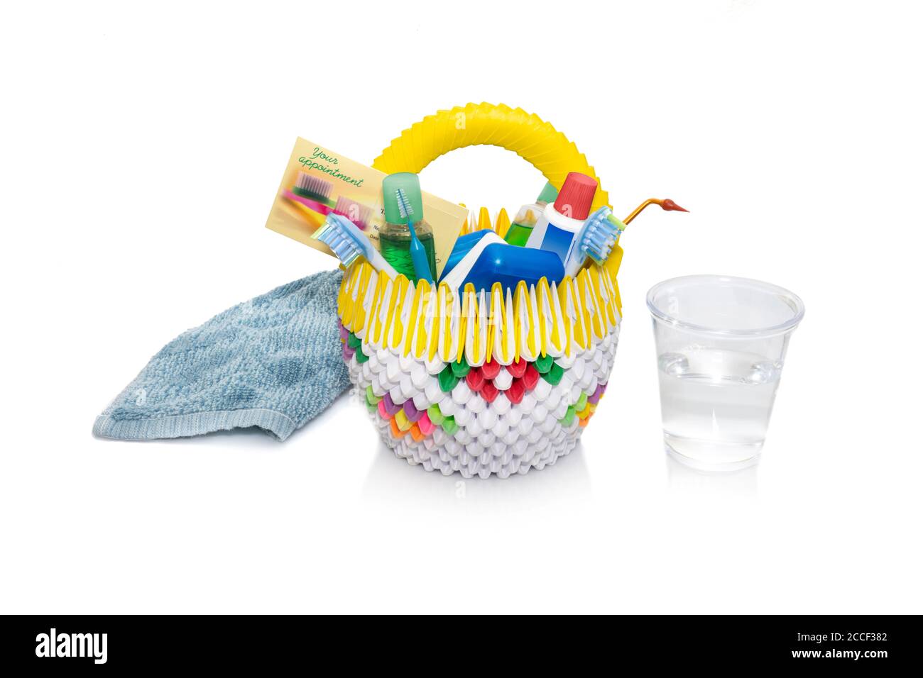 Dental healthcare items in a colorful basket: towel, glass of water ...