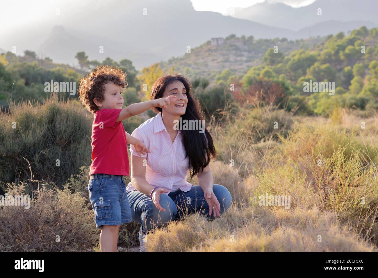 Mother and son on excursion in the field crouching down and observing ...