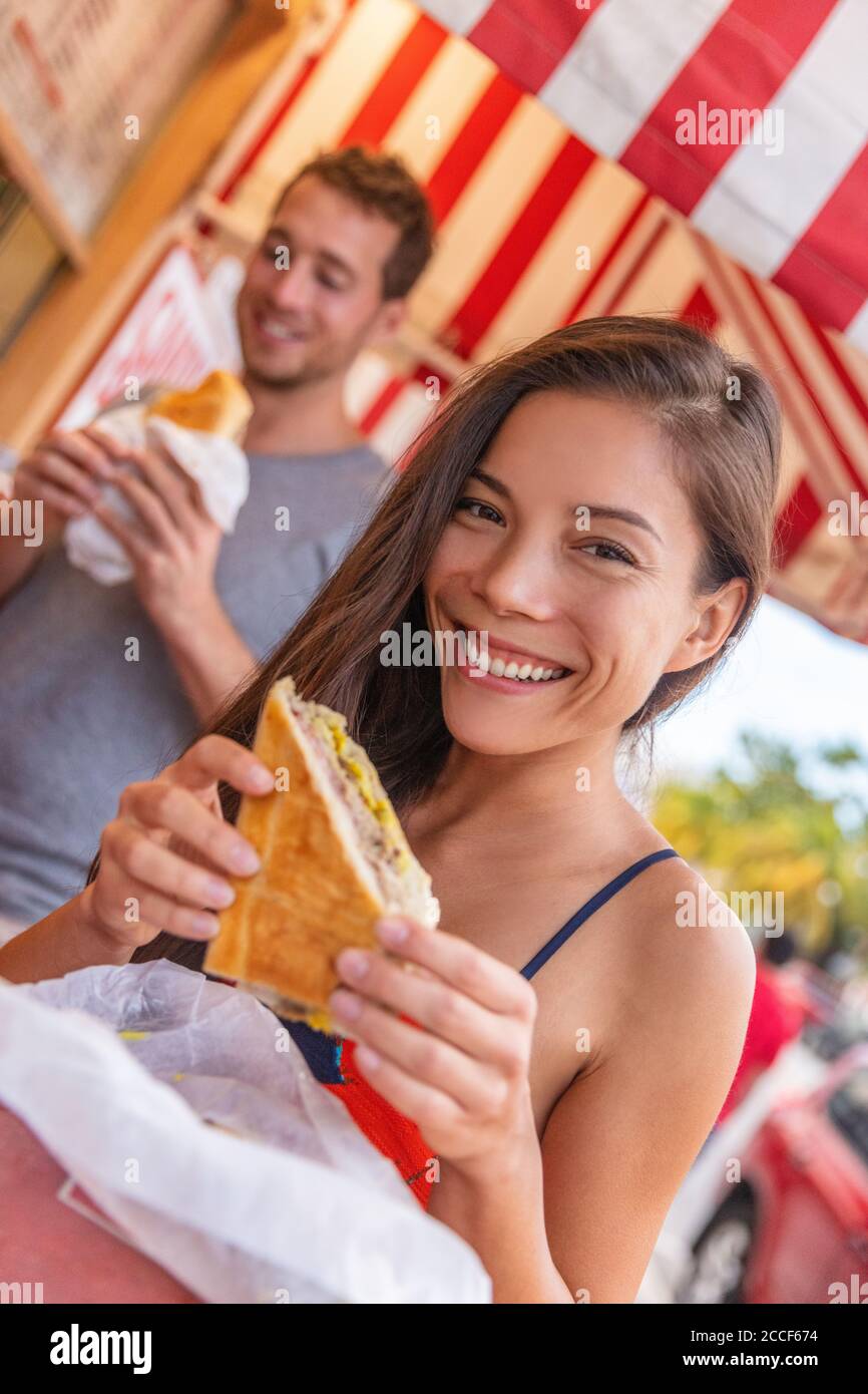 Happy Asian girl eating cuban sandwich at local cafe restaurant in Key ...