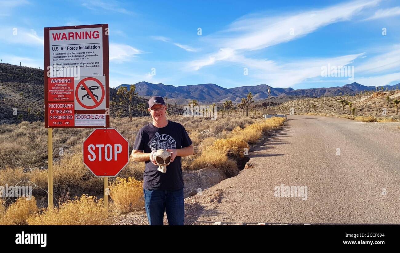A tourist stands at the border of Area 51 holding an alien skull ...