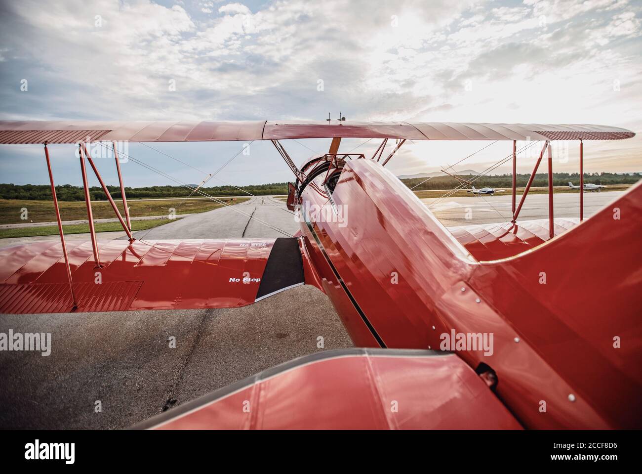 Red shiny restored vintage airplane on airfield at sunrise in Maine ...