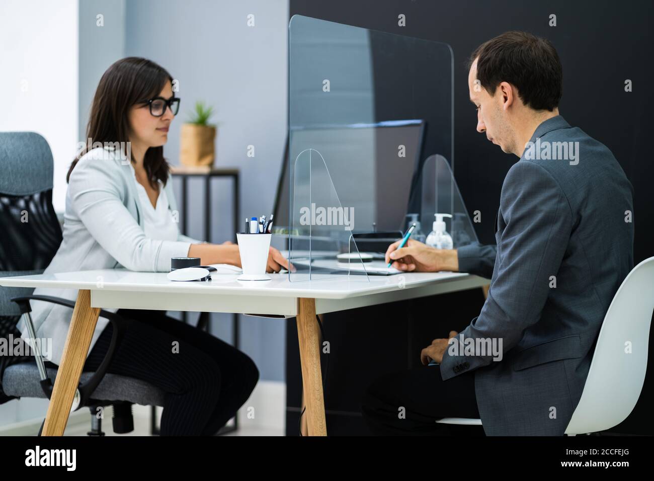 Client Signing Contract At Desk Protected By Sneeze Guard Stock Photo ...