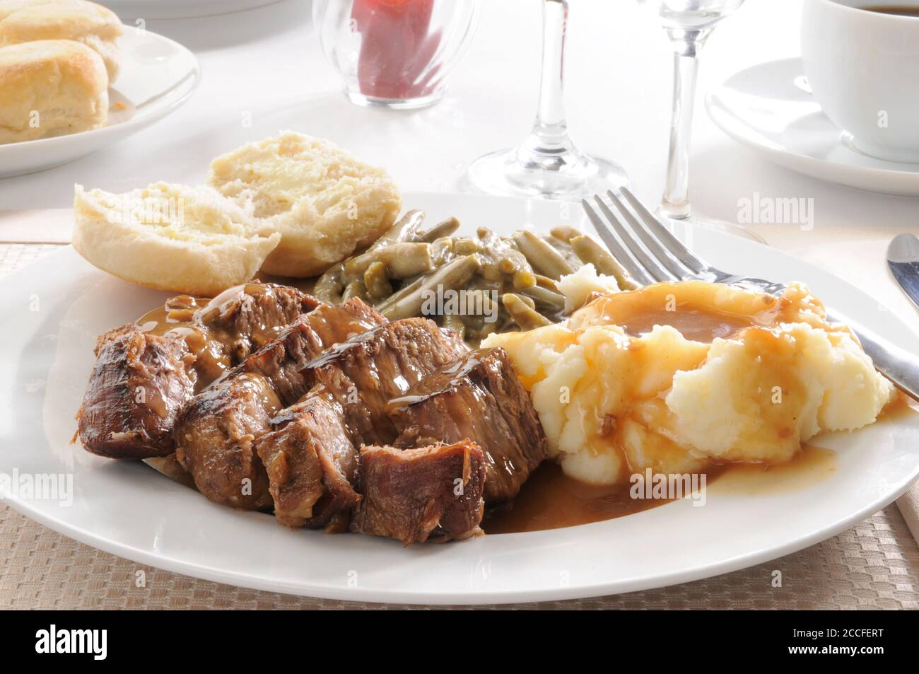 A plate of sliced beef pot roast with mashed potatoes and mushroom ...