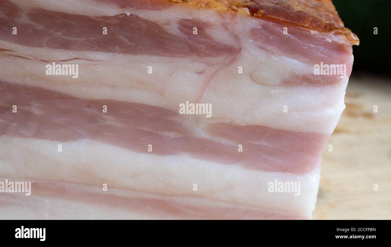 Smoked bacon meat with lots of fat on it in closeup. The meat is salt ...