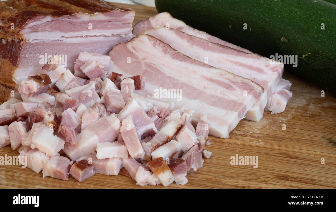 Smoked bacon meat with lots of fat on it, diced and sliced in closeup ...