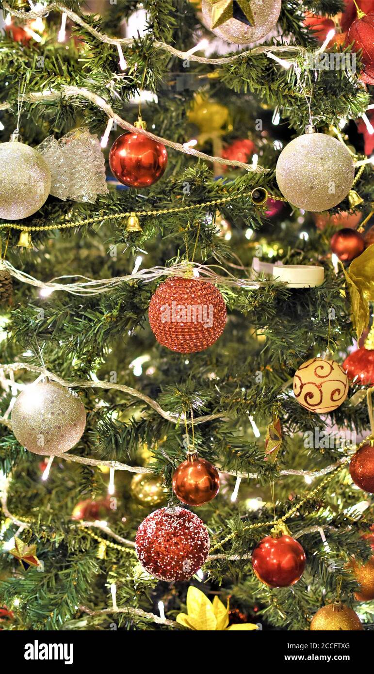 Glittering red and white balls, ribbons, and fairy lights adorn a green ...