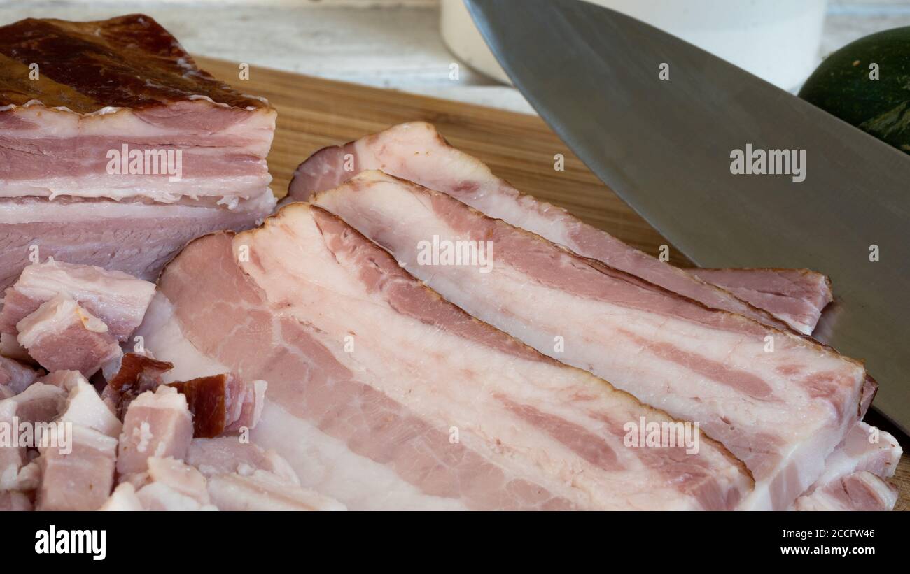 Smoked bacon meat with lots of fat on it, diced and sliced in closeup ...