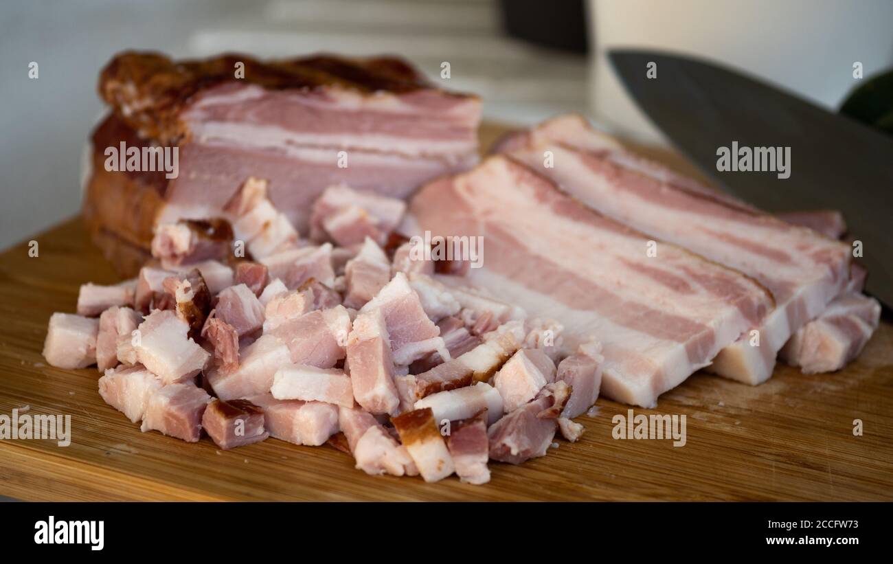 Smoked bacon meat with lots of fat on it, diced and sliced in closeup ...