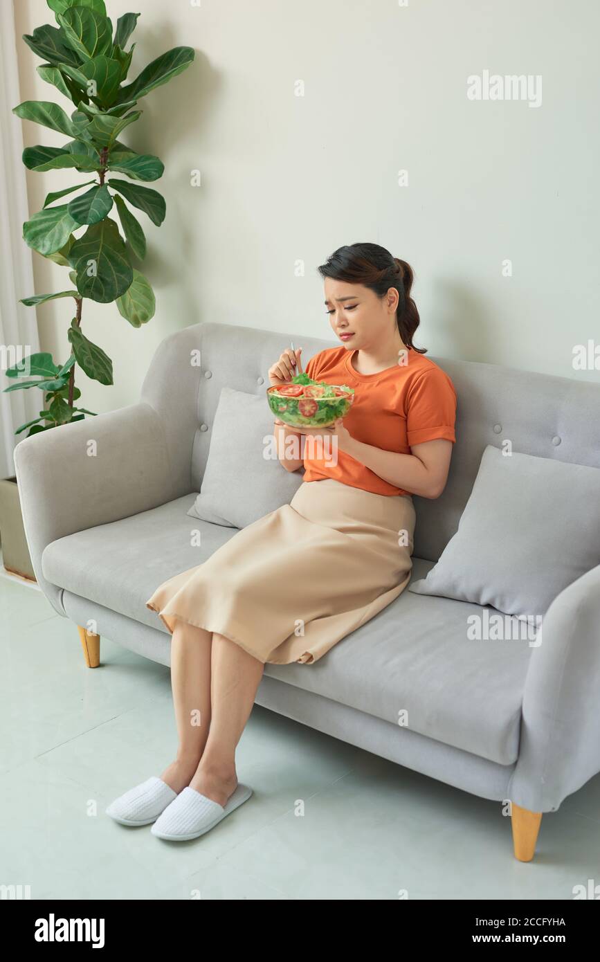 Beautiful woman on the sofa eating a healthy salad Stock Photo - Alamy