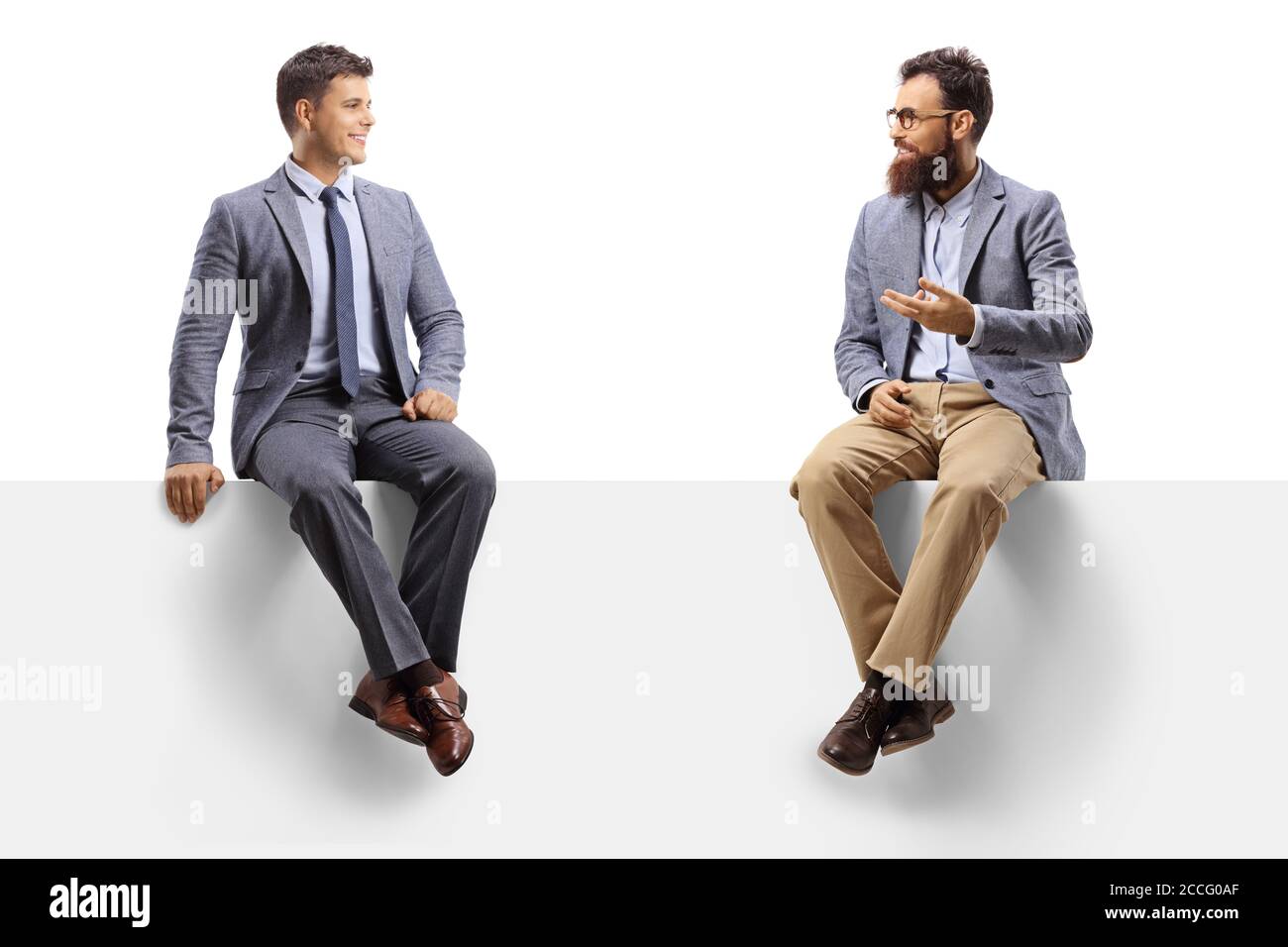 Two male friends sitting on a blank panel and talking isolated on white ...