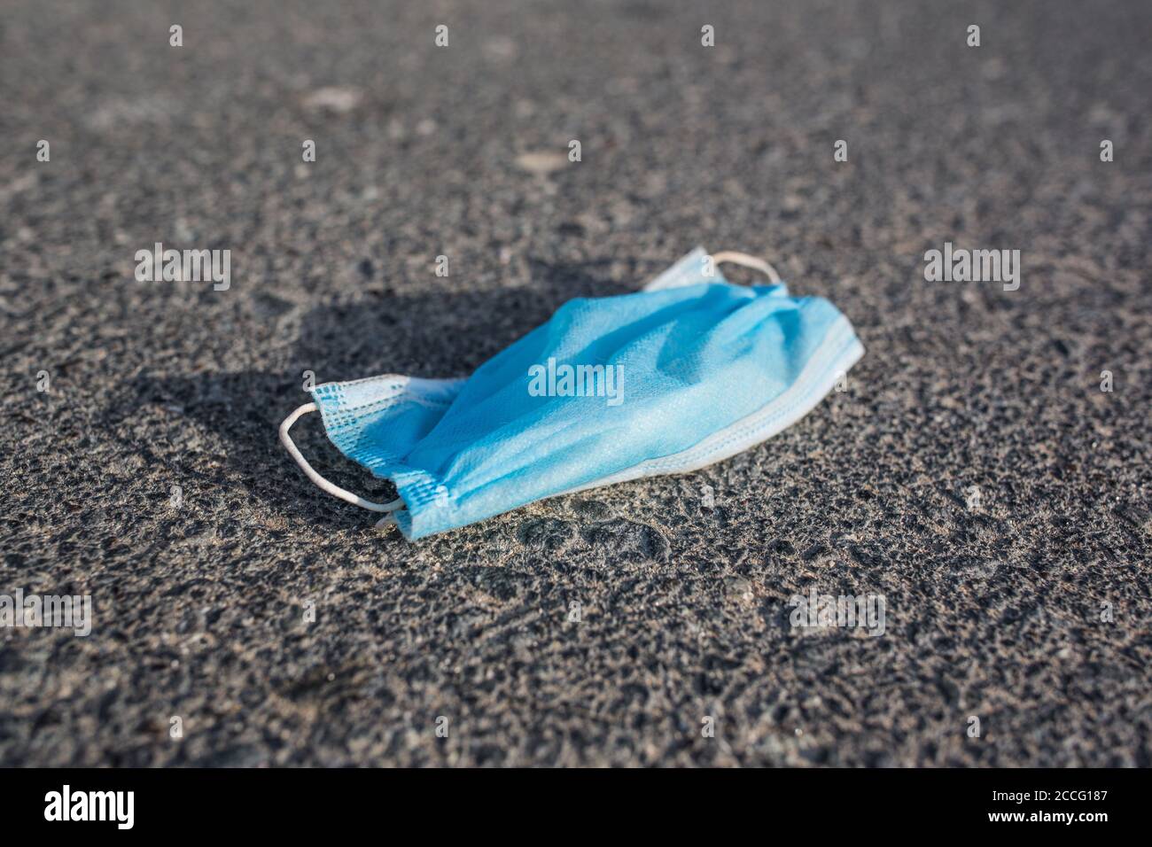 Used medical face mask discarded on the pavement of a public street ...