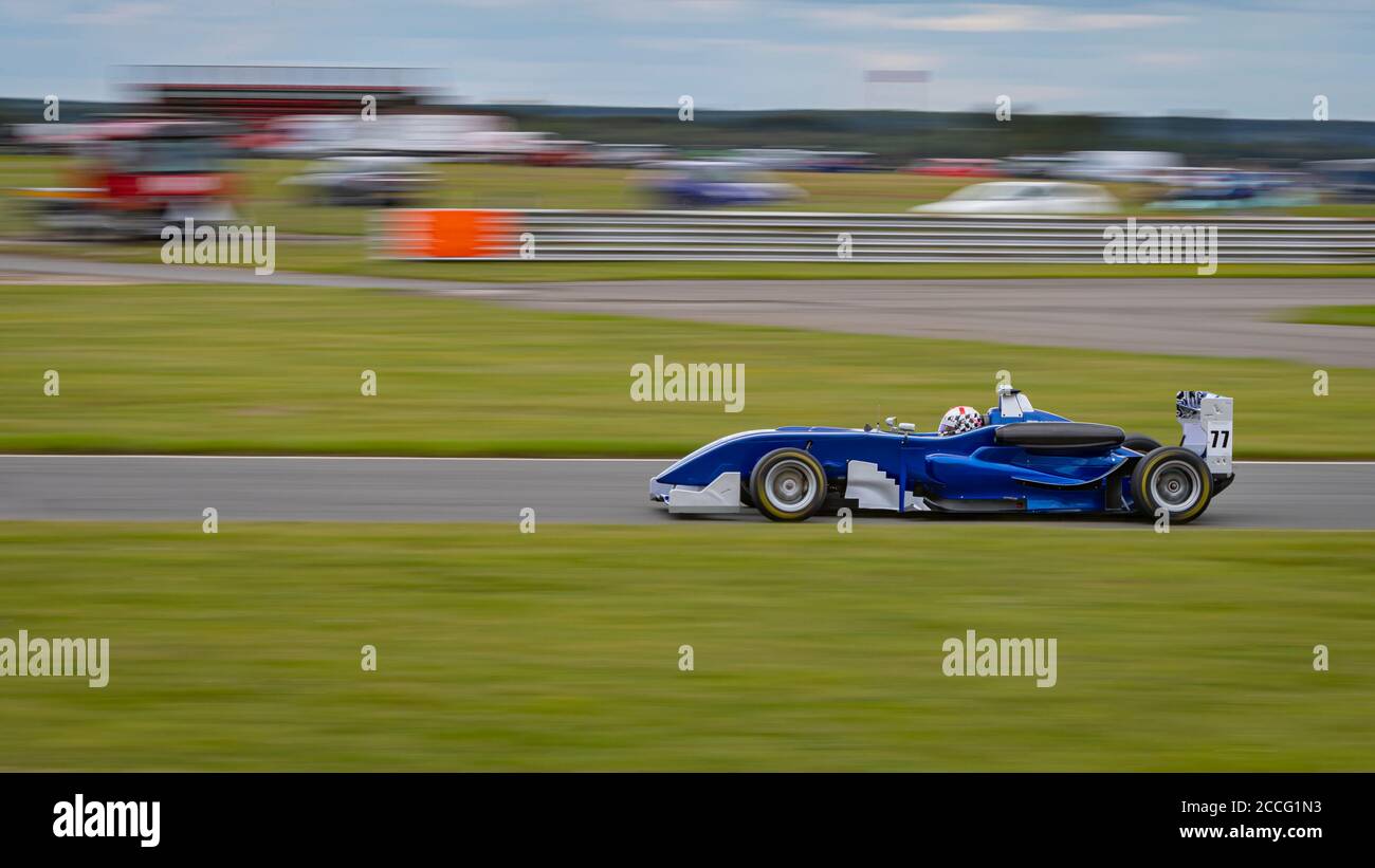 A panning shot of a blue and white racing car as it circuits a track ...