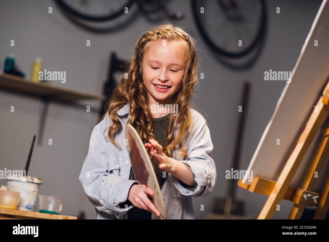 An art school student mixes colors on a palette for her canvas drawing ...