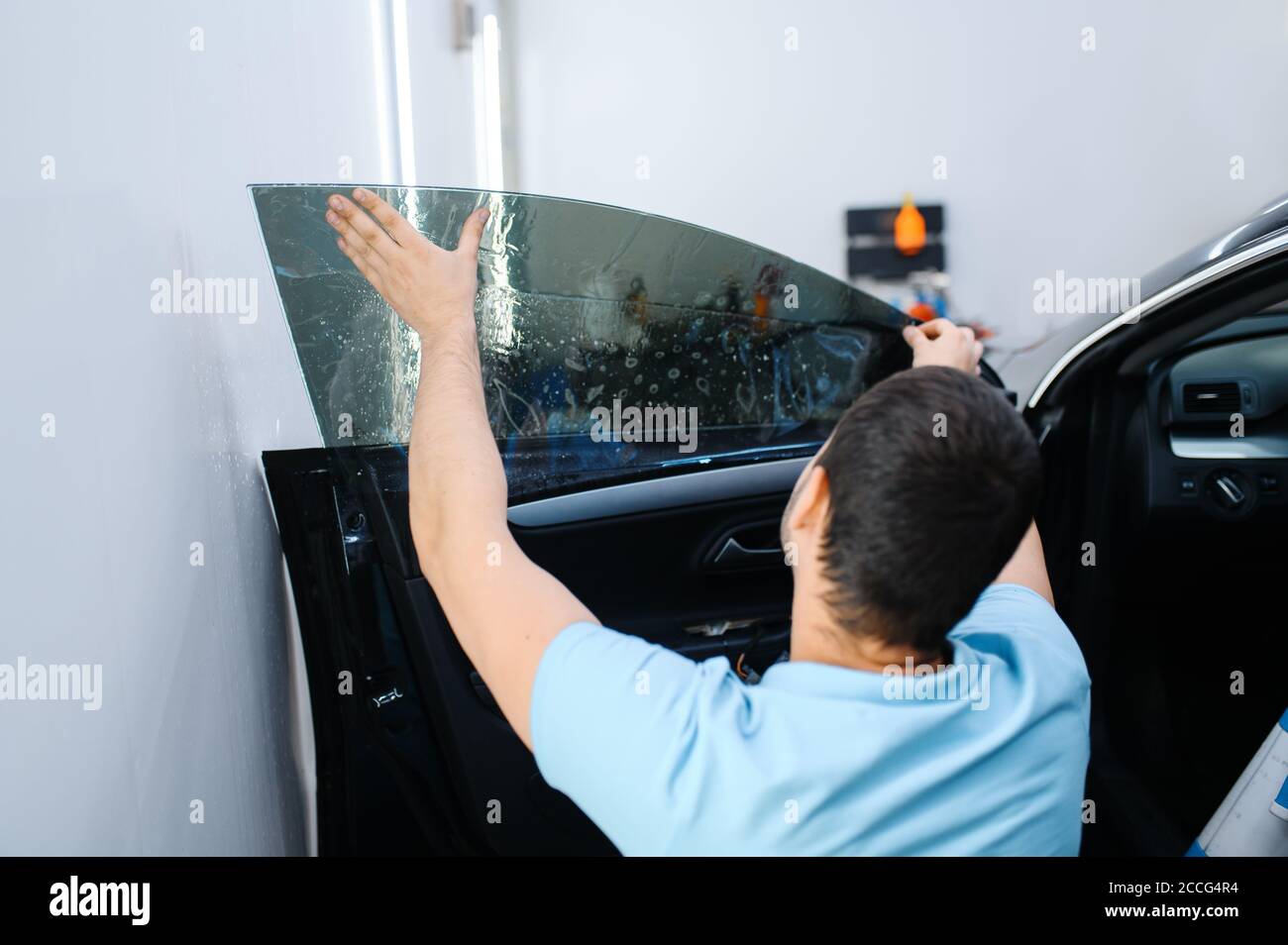 Male worker tries on sheet of car tinting Stock Photo - Alamy