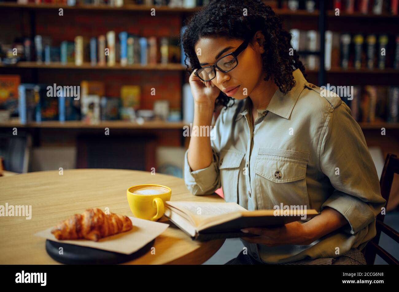 Female student reads book in library cafe Stock Photo - Alamy