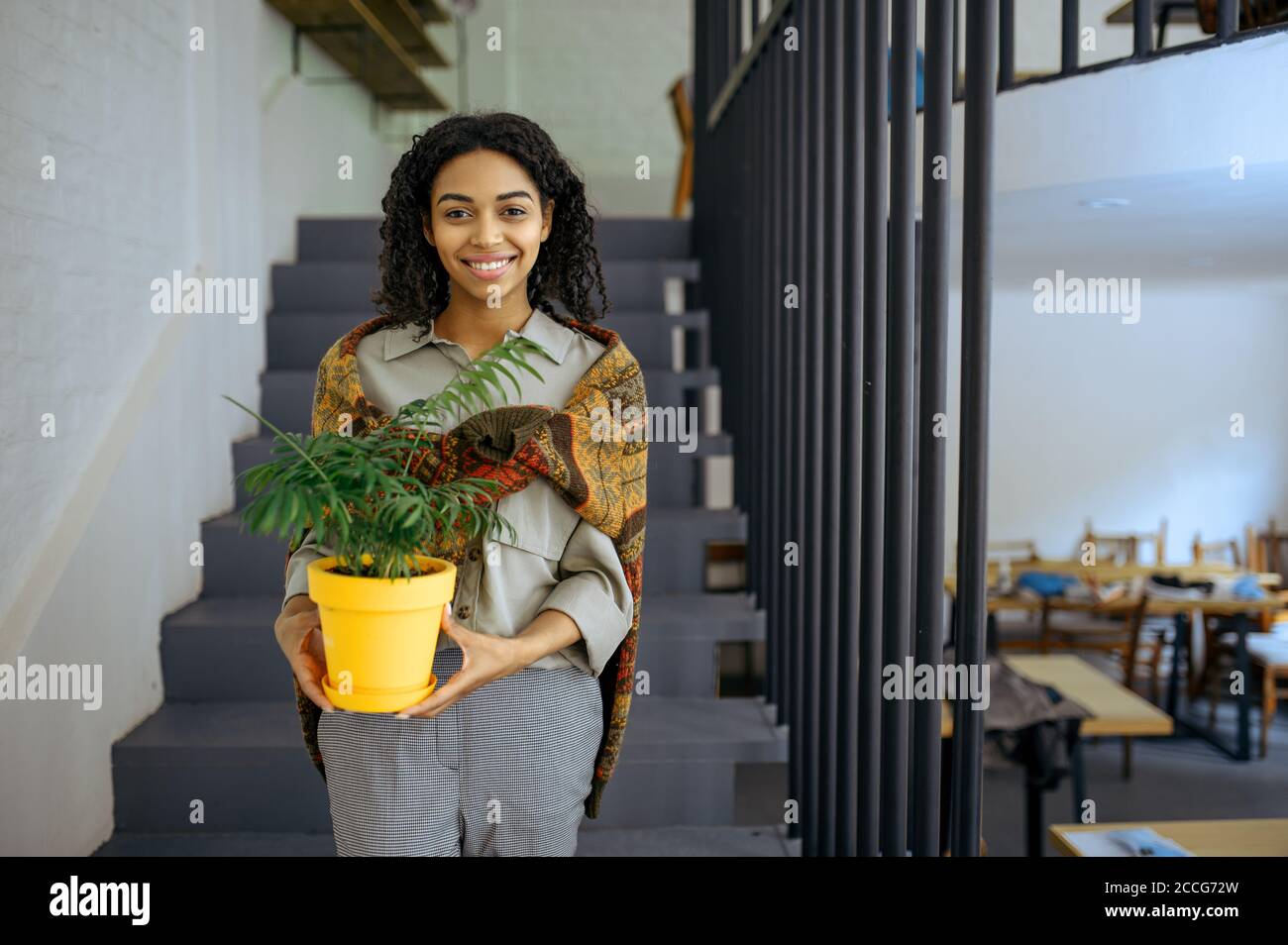 Pretty female student holds flower in a pot Stock Photo - Alamy