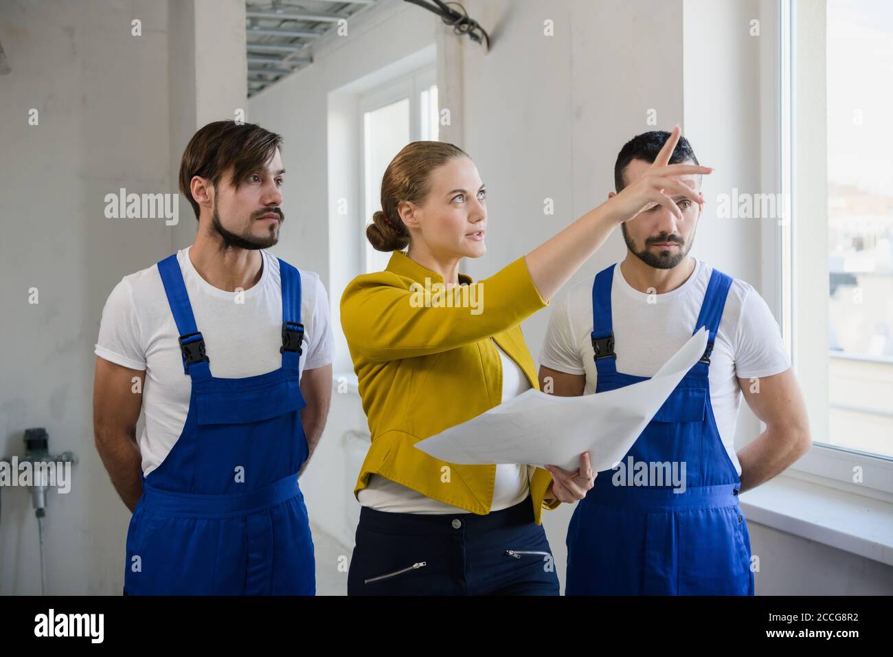 A client with a plan in her hands is talking to two construction ...