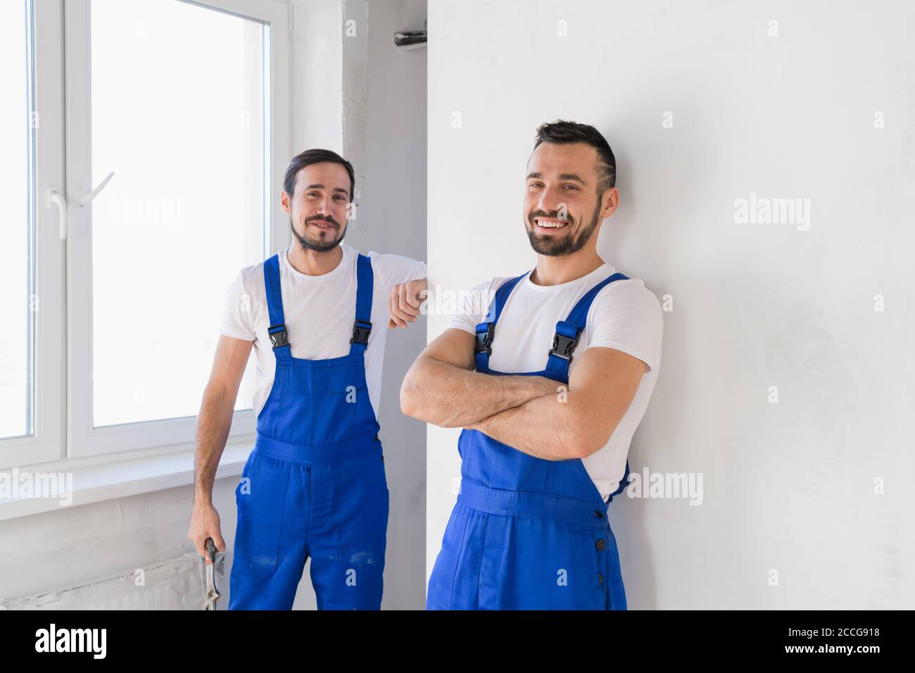 Two bearded workers in blue overalls posing for a photo Stock Photo - Alamy