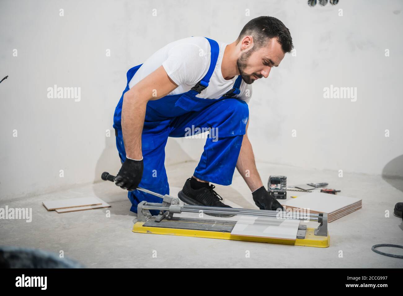 The general laborer measures the tiles and cuts them with a ceramic saw ...