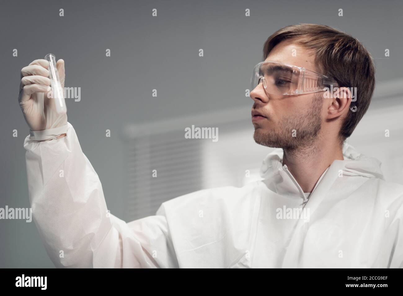 Closeup portrait of a man holding a test tube with white turbid liquid ...