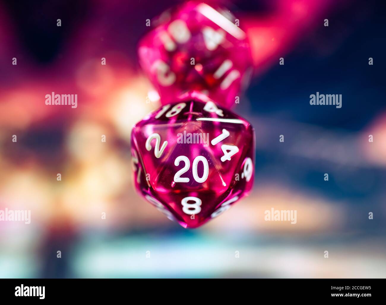 Close up of a transparent pink polyhedral dice against a blurry ...