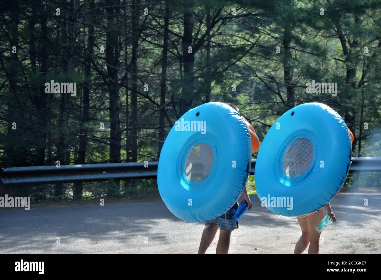 Two people carrying inflated tubes for river raftig Stock Photo - Alamy