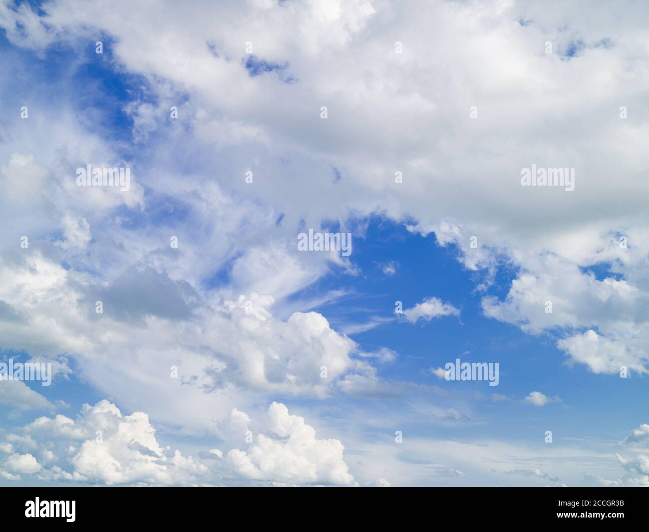 Blue summer sky with white cumulus clouds illuminated by sunlight ...
