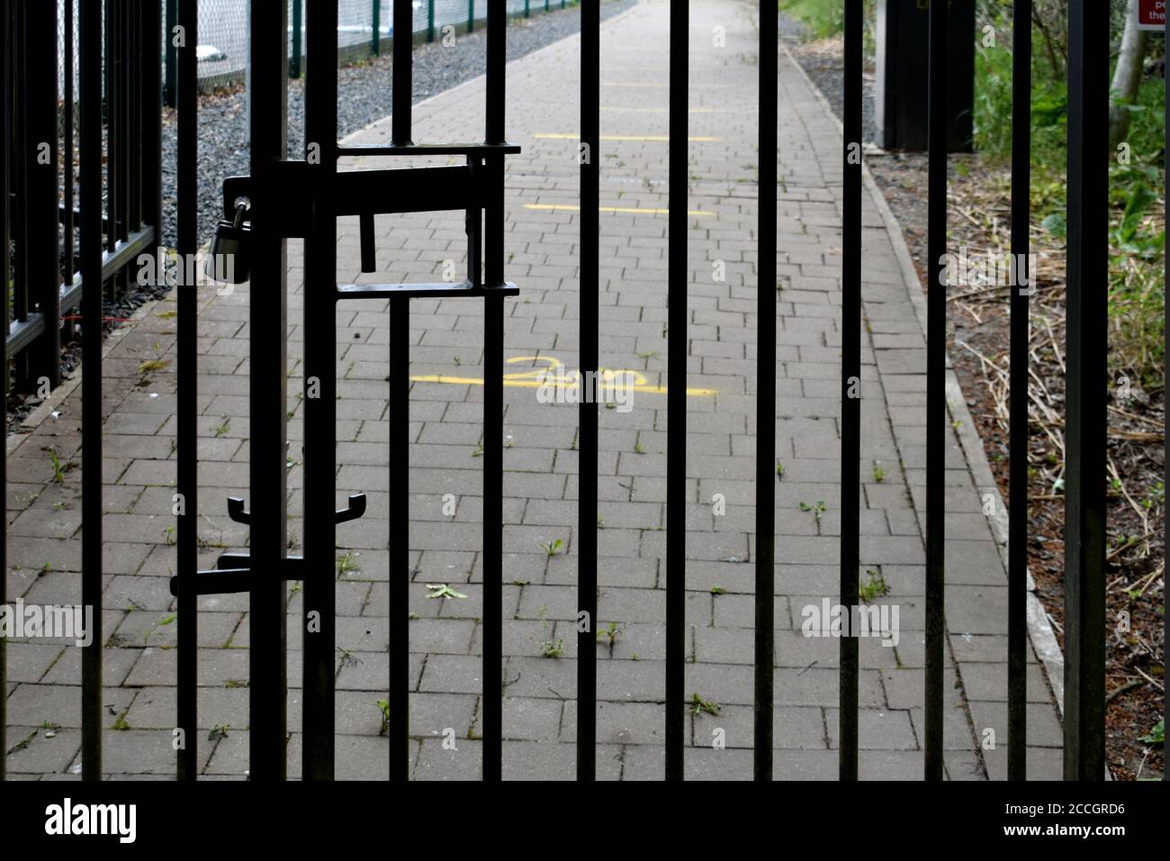 close up of metal school gates with pad lock and yellow Exit only sign ...