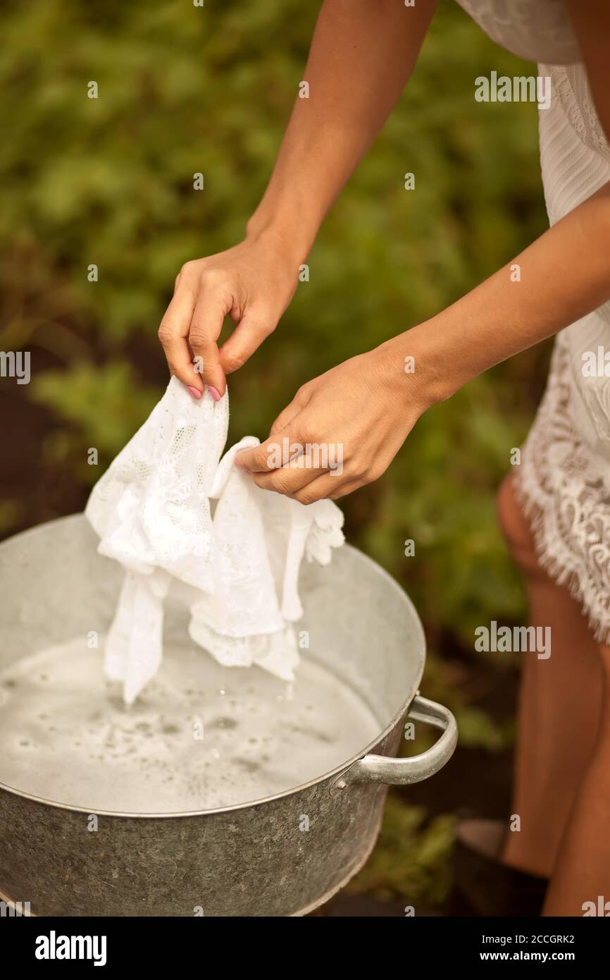 Woman washing clothes by hand in a tin basin. Retro style. Hand washing ...