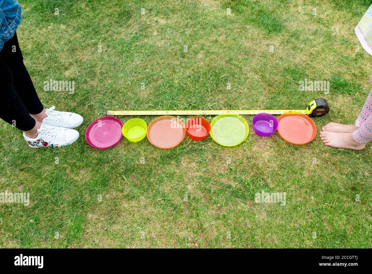 Children's legs by colourful plates and dishes against a tape measure ...