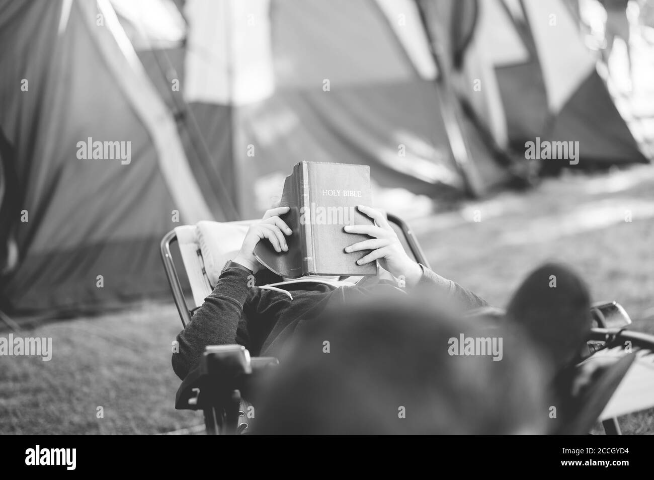 Grayscale shot of male lying and reading the Holy Bible Stock Photo - Alamy