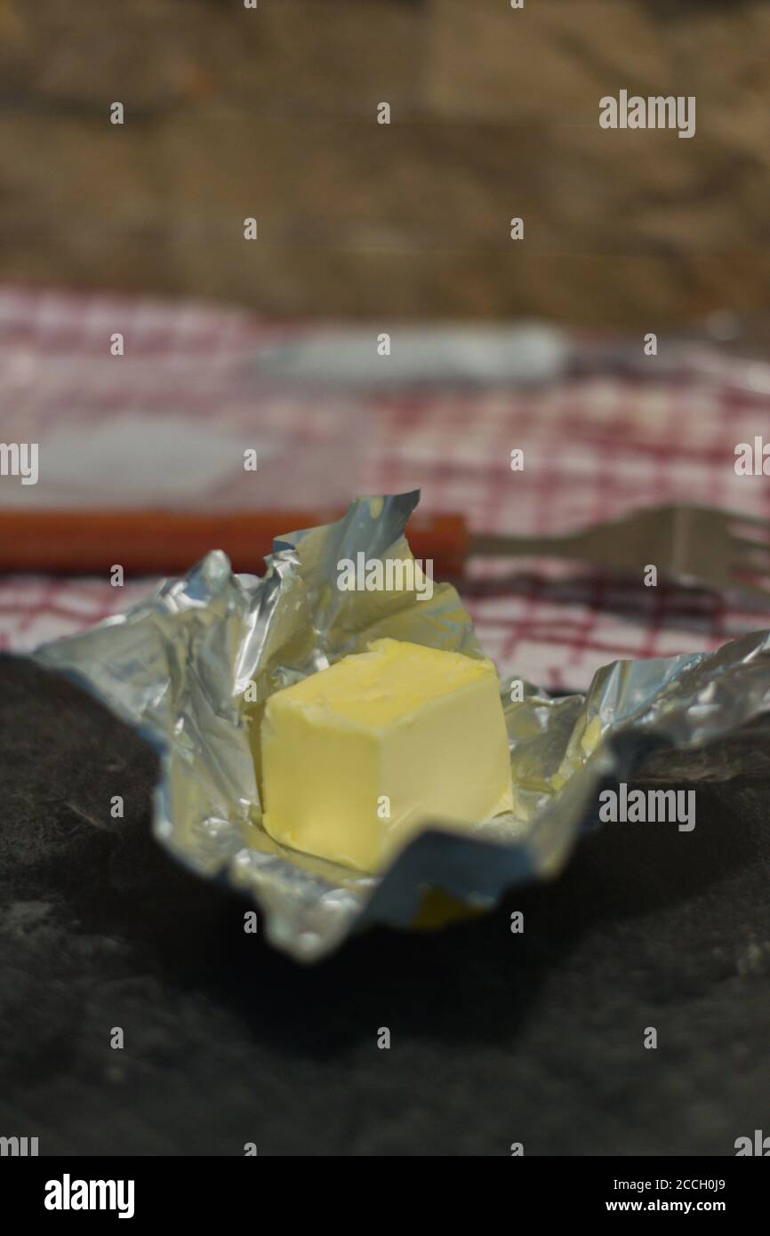 Vertical closeup shot of a block of butter in tinfoil on a table Stock ...