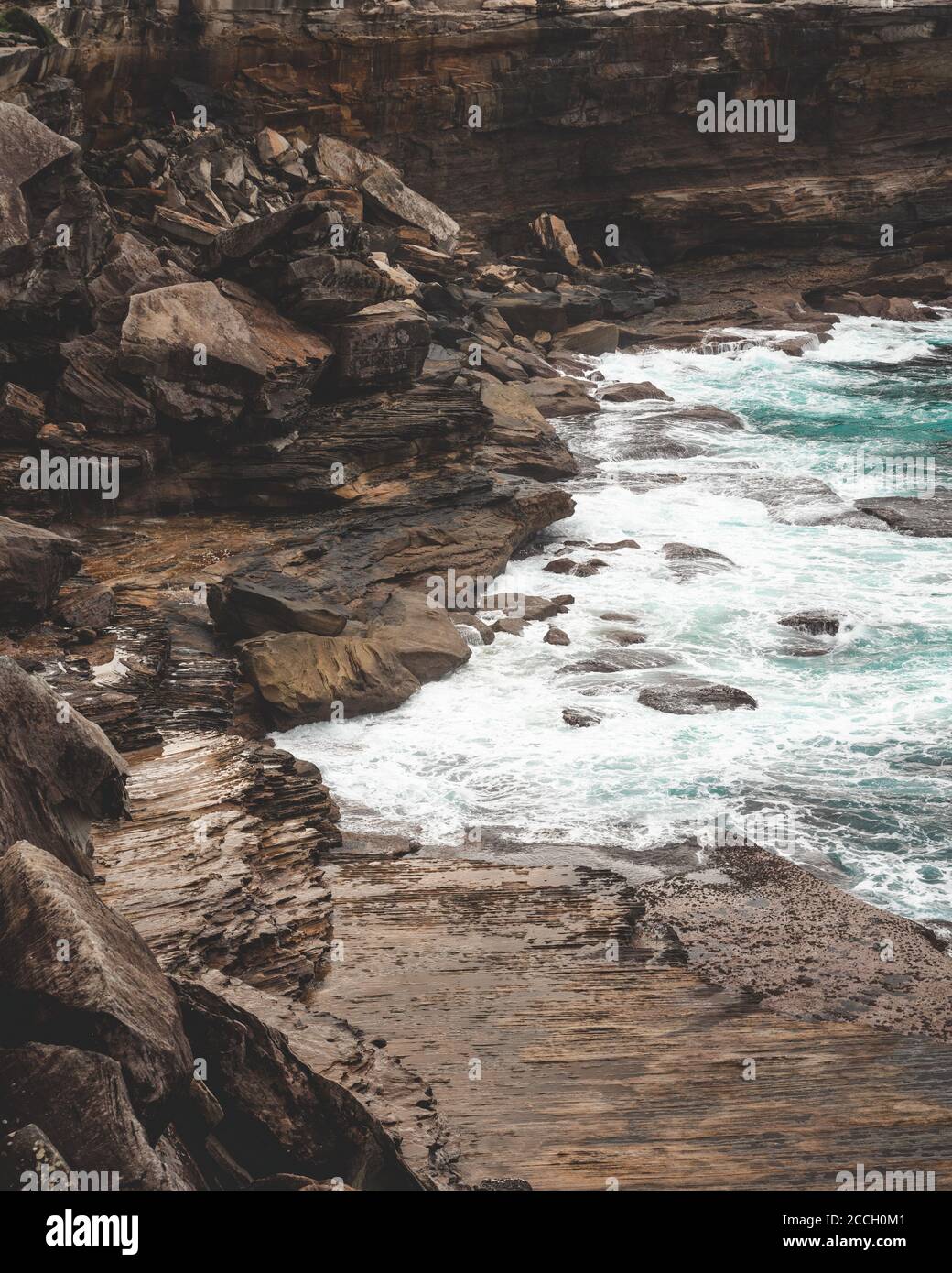 Beautiful vertical shot of a large cliff next to blue water on a gloomy ...